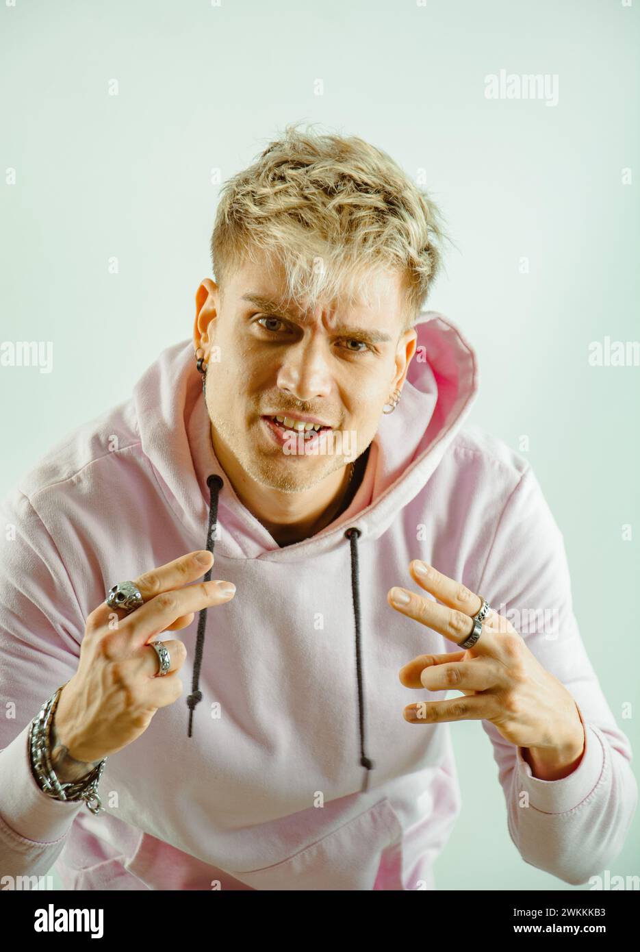 A man wearing a pink hoodie is standing with his hands outstretched in ...
