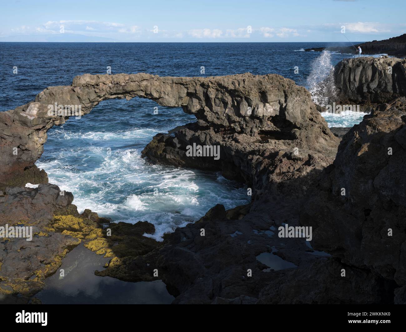 Angler at the rugged, volcanic coastal cliffs and arches of El Hierro ...