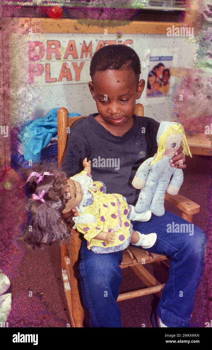 Black boy plays with dolls in "dramatic play" area of his Head Start ...