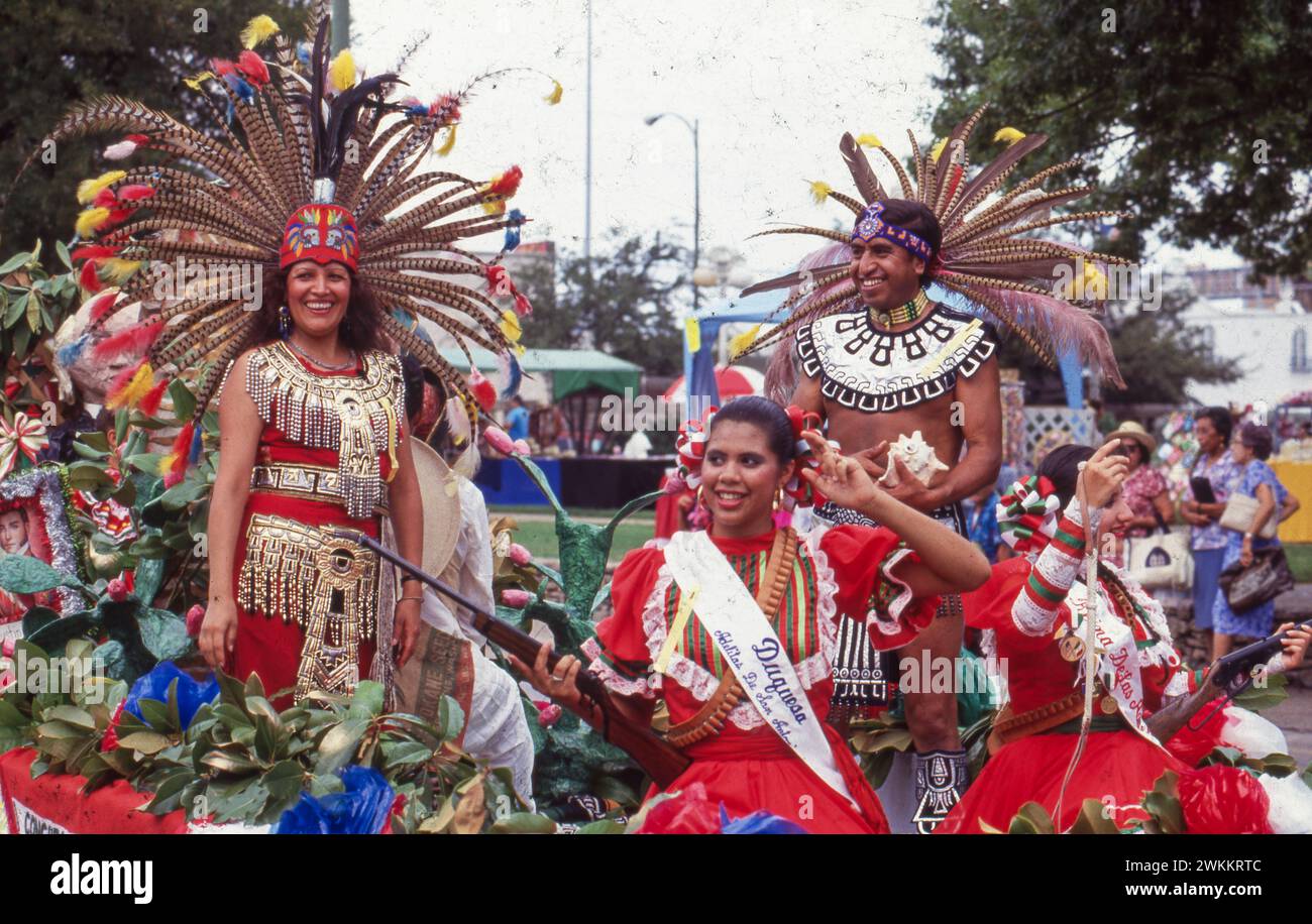 Teens wearing indigenous Mexican costumes ride on float during parade ...