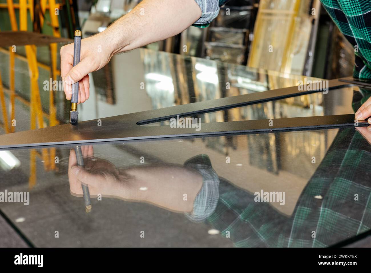 A glazier cuts glass in a glass factory, cutting thick glass ...