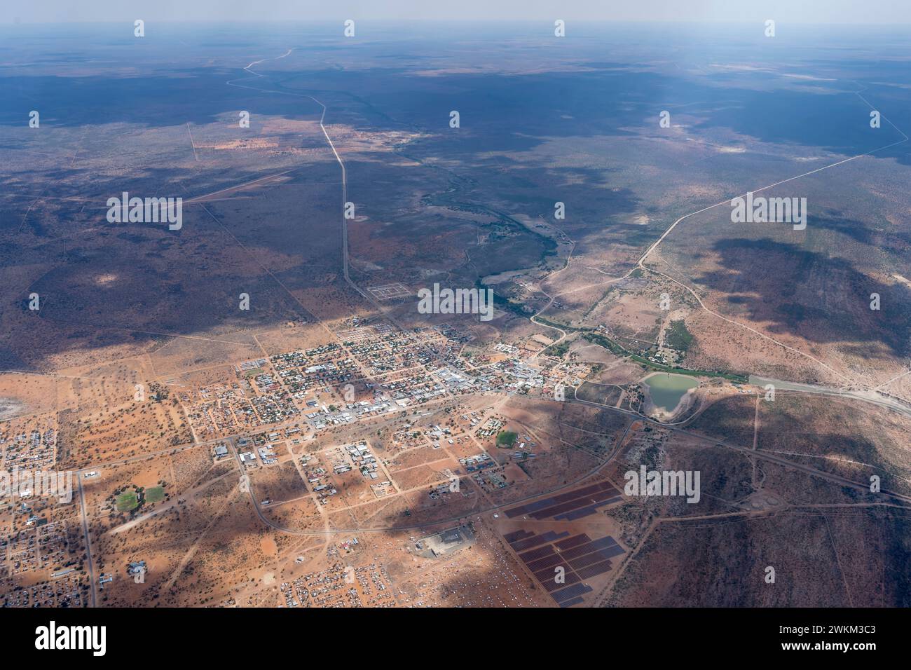 aerial cityscape with town near river in desert, shot from a glider ...