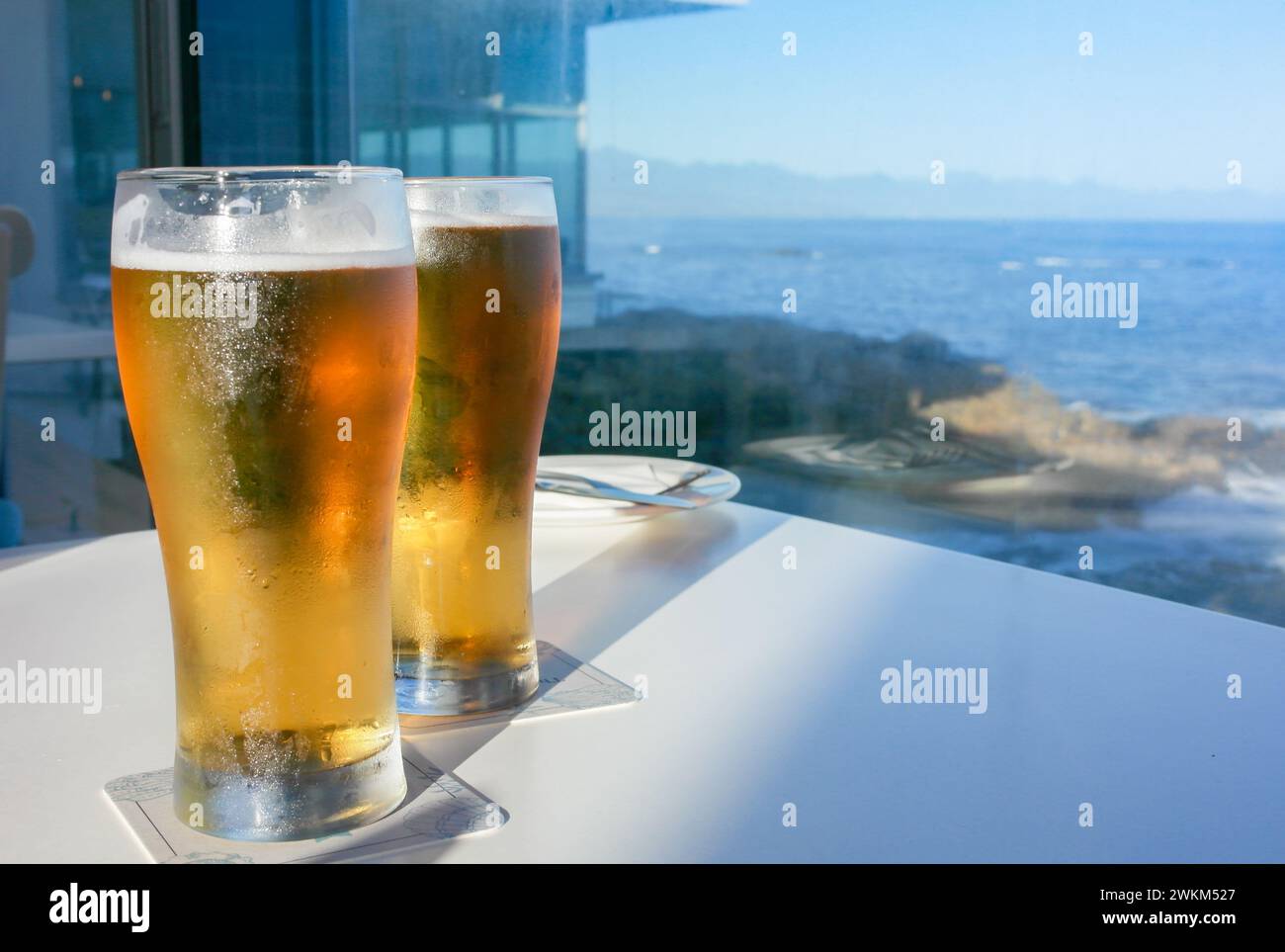 Two ice cold beers on a table outdoors at sun down - selective focus ...
