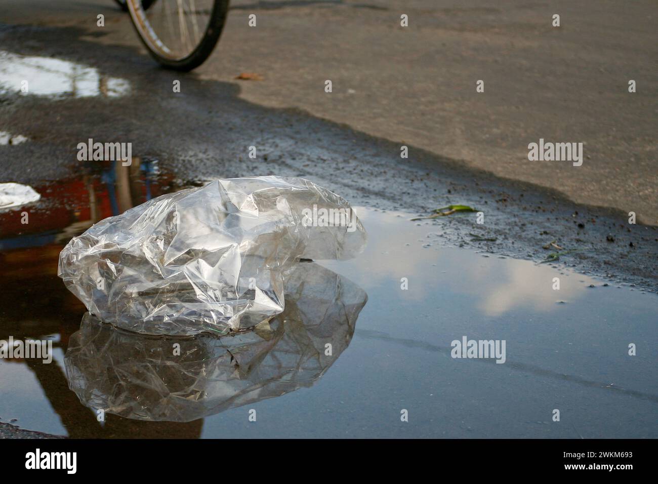 Transparent plastic trash in a puddle on the street Stock Photo - Alamy