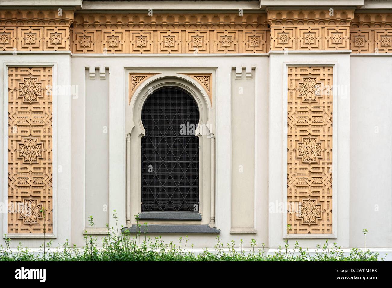 Wndow with a metal grill against a white wall framed by a pattern ...