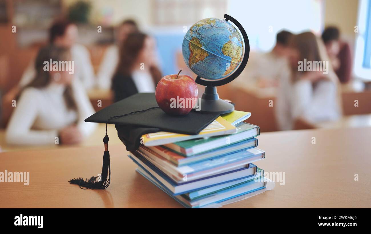 A globe of the world with textbooks and a college graduate's cap in a ...