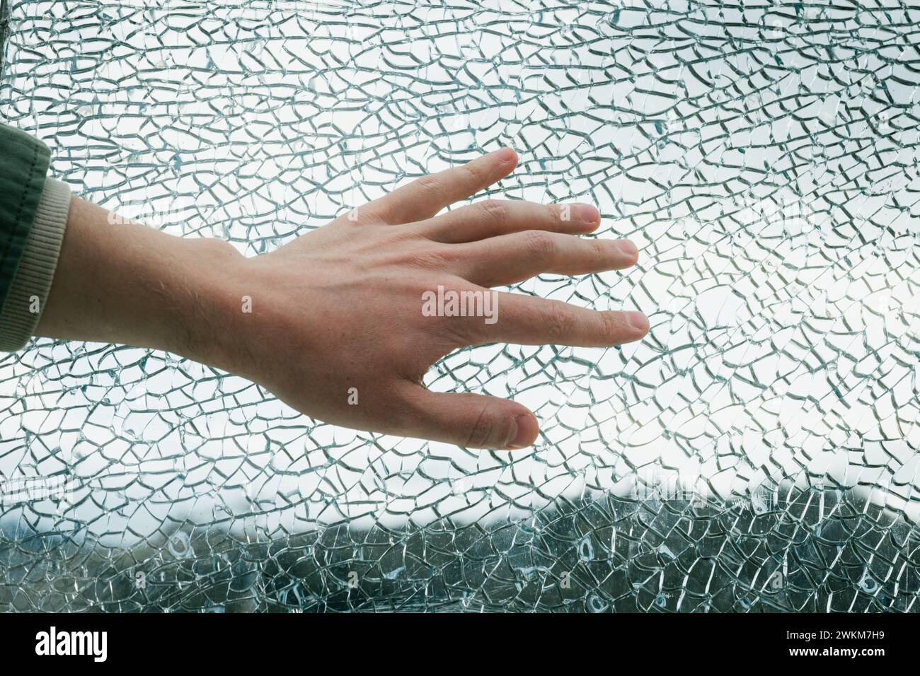 Hand touching broken glass window. Close-up view of shattered glass ...