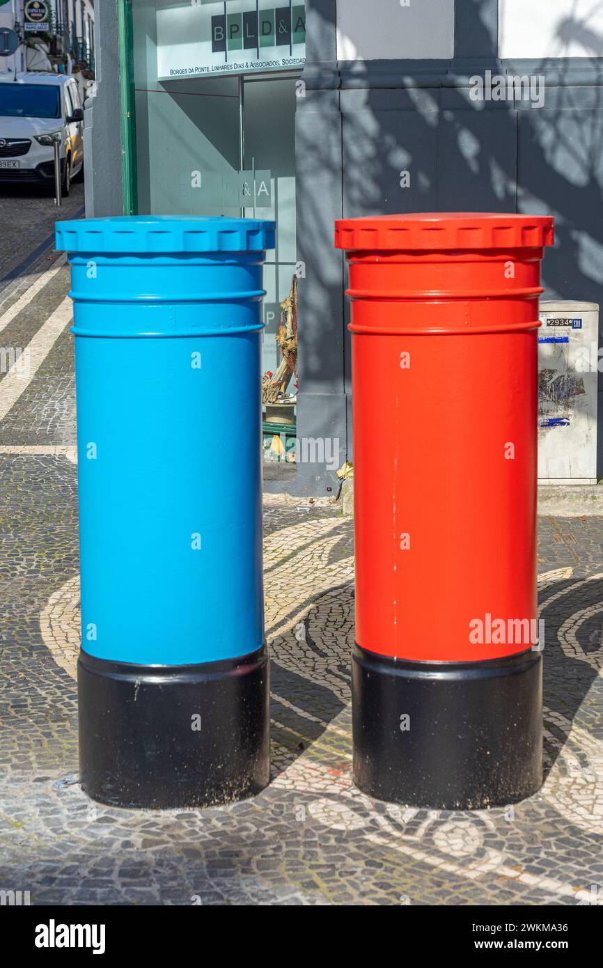 two cylindrical-shaped mailboxes, one red and the other blue. Ponta ...