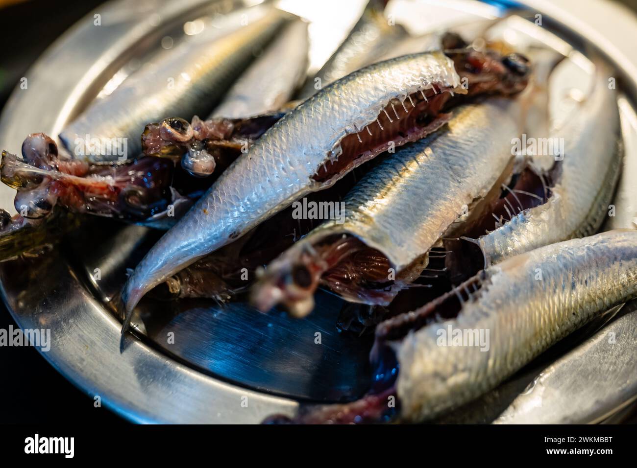 fresh sardines at a bustling fish market, their scales shimmering with ...
