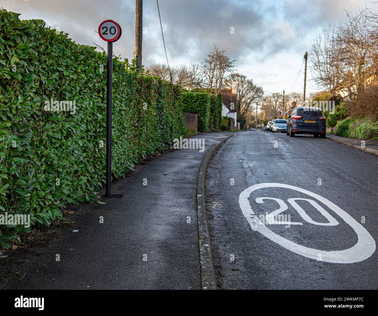 Residential street with 20 mph speed limit signs on a cloudy day with ...