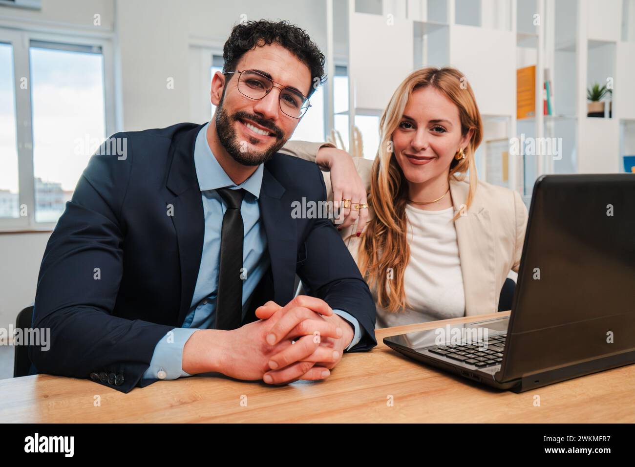 Teamwork of businesspeople sitting on desk and looking at camera. Two ...