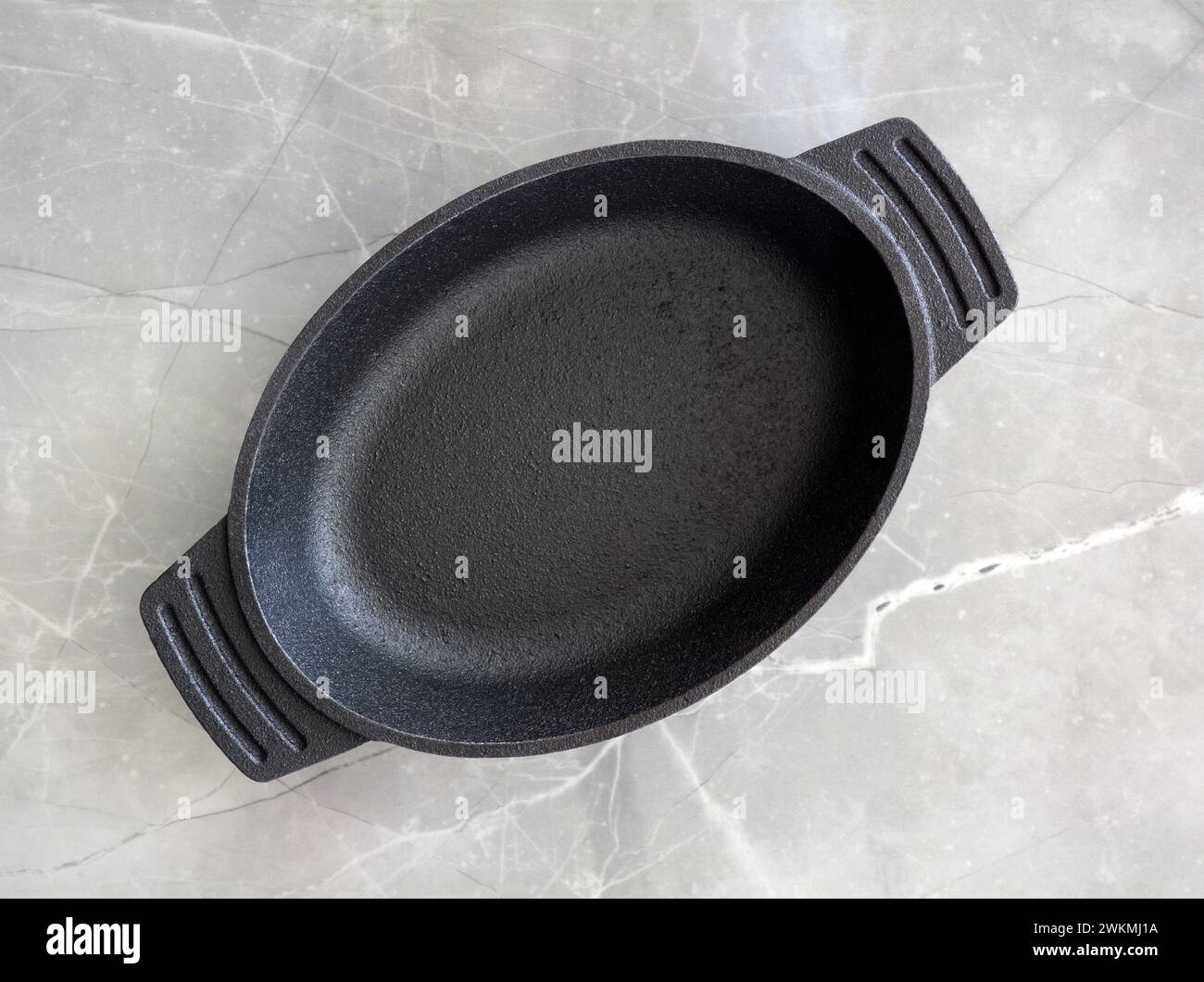 Cast iron casserole dish on marble background in flat lay composition ...