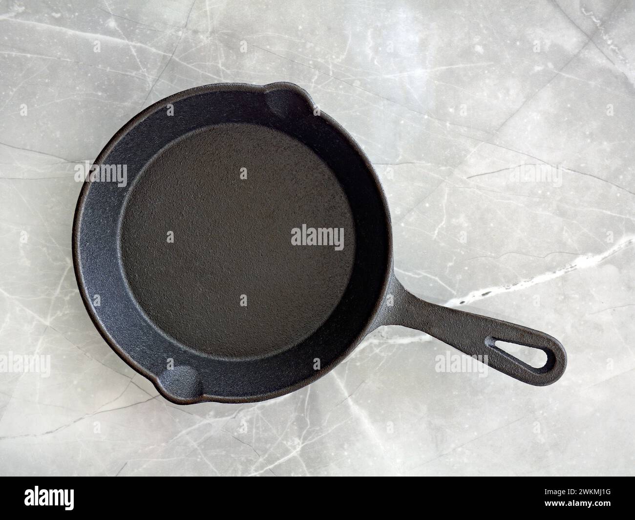 Cast iron skillet on grey marble background in flat lay composition ...