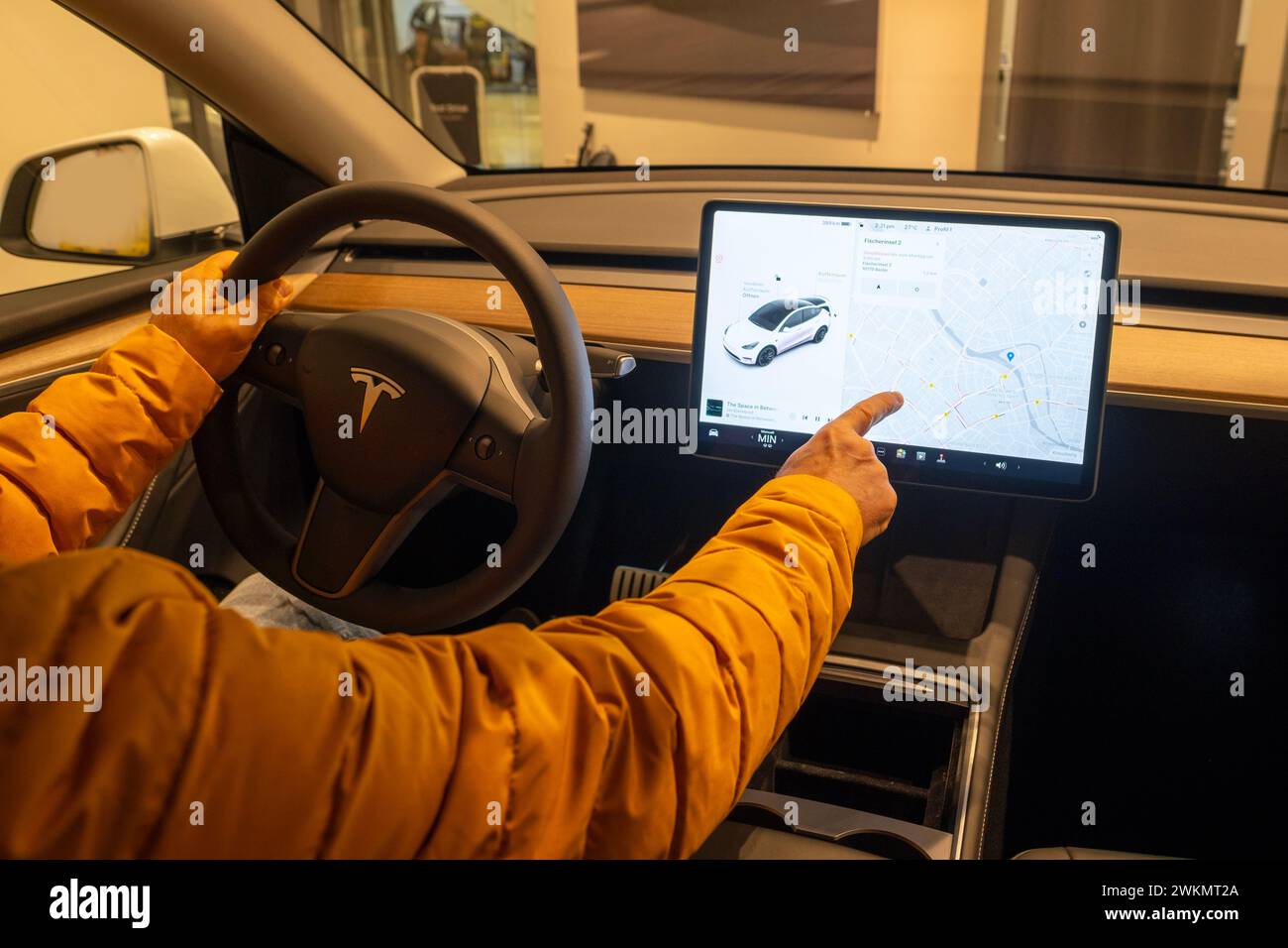 Close-up male hands uses display, gripping steering wheel Tesla model Y ...