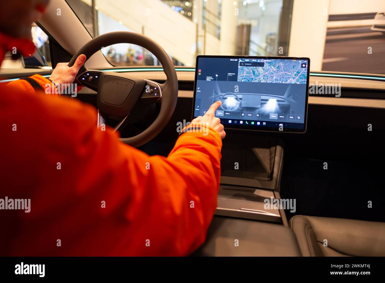 Close-up male hands uses display, gripping steering wheel Tesla model Y ...