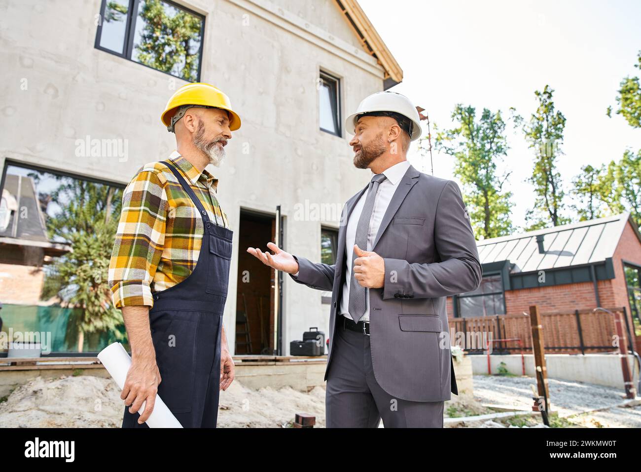 jolly cottage builder and architect in suit and overalls with blueprint ...