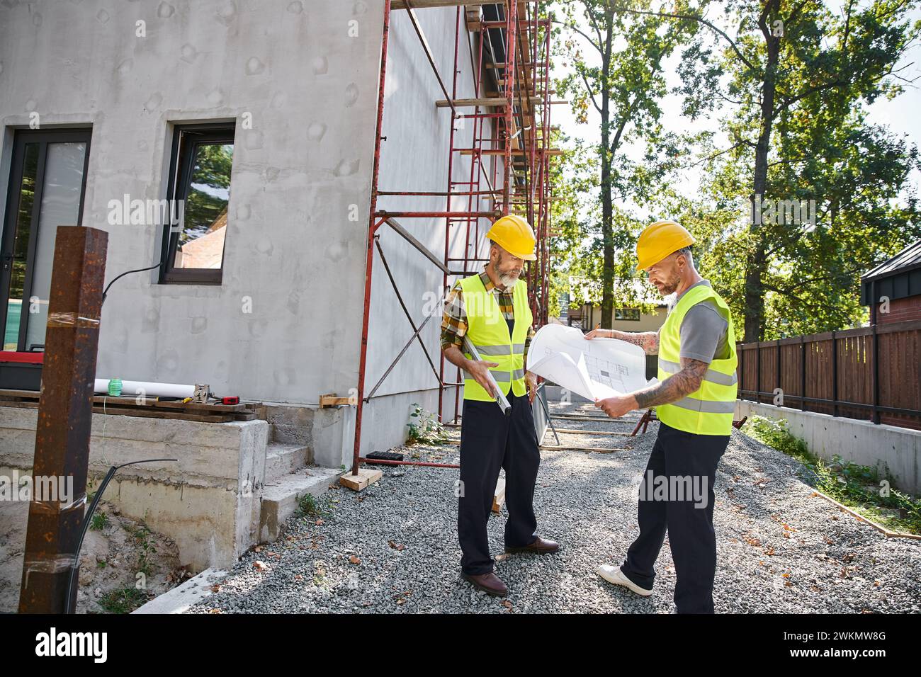 good looking dedicated cottage builders working hard with blueprints ...