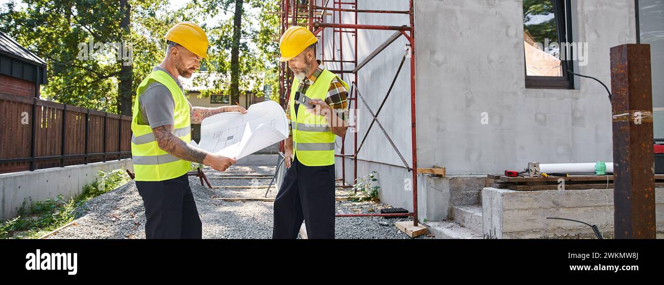 good looking cottage builders working hard with blueprints and level on ...