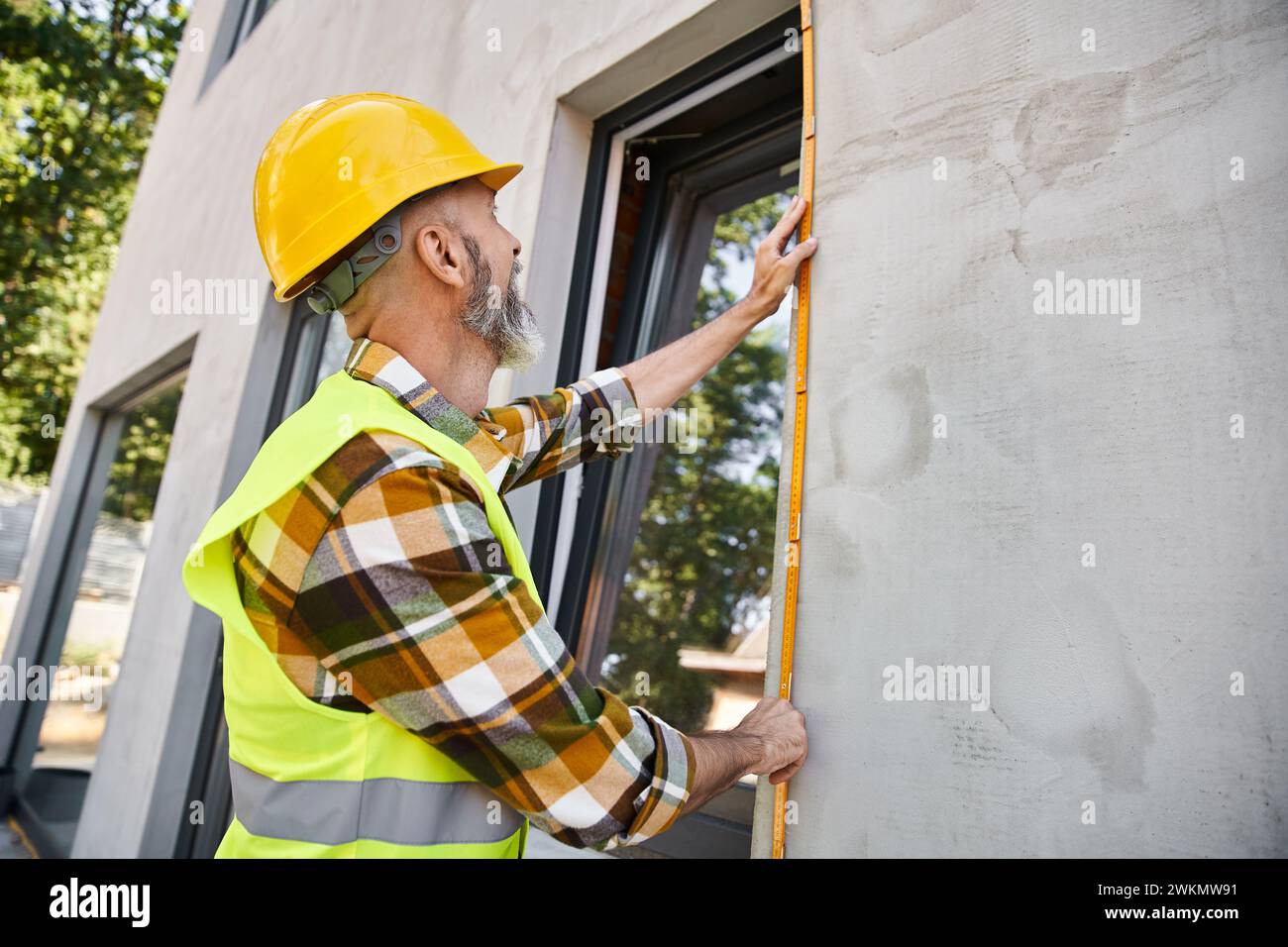 good looking hardworking construction worker with beard measuring ...