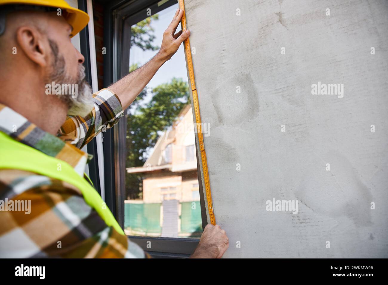good looking hardworking construction worker with beard measuring ...