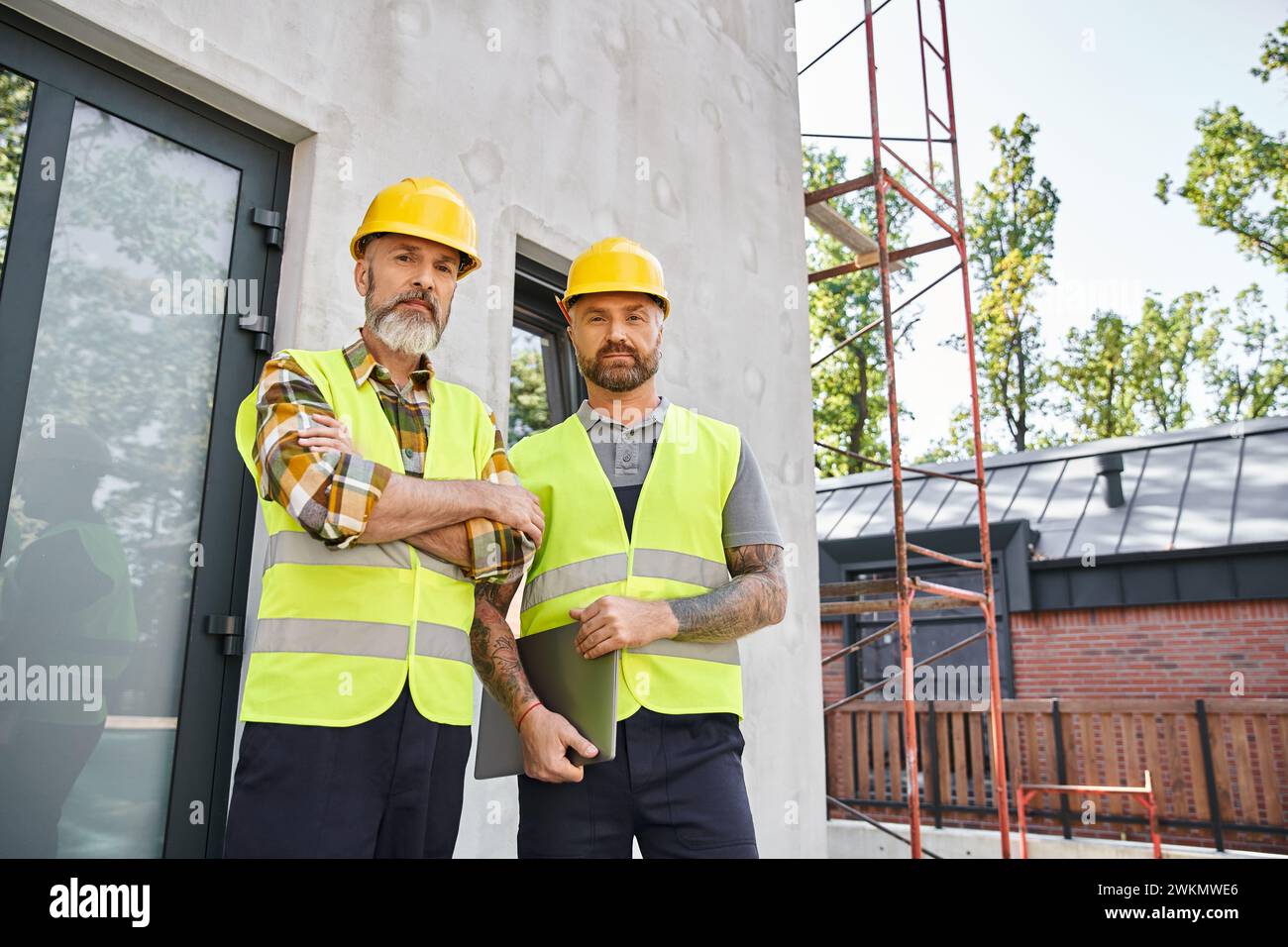 good looking devoted men in safety attires with laptop looking at ...
