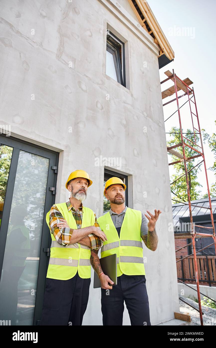 two good looking construction workers in safety vests and helmets ...