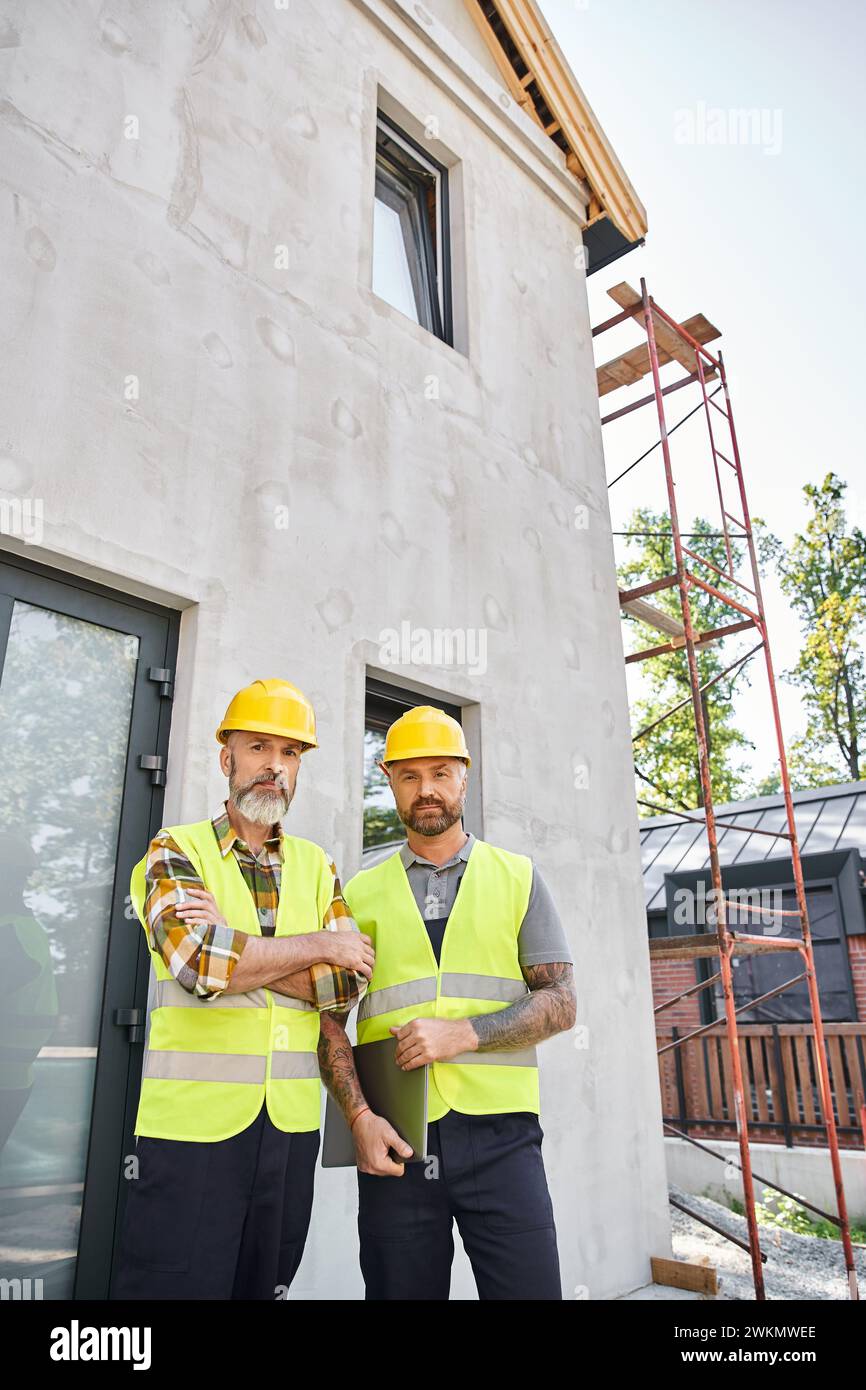 good looking devoted men in safety attires with laptop looking at ...