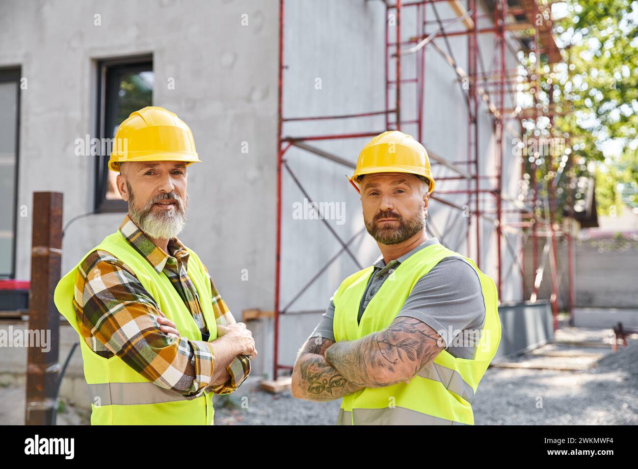 good looking cottage builders in safety helmets posing next to ...