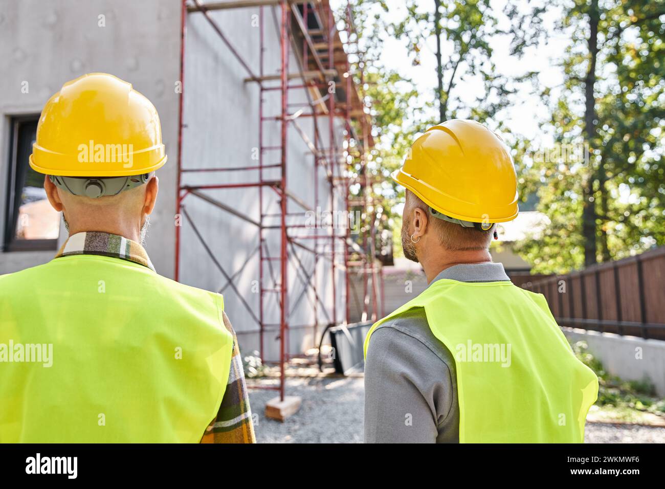 back view of cottage builders in safety helmets looking at scaffolding ...