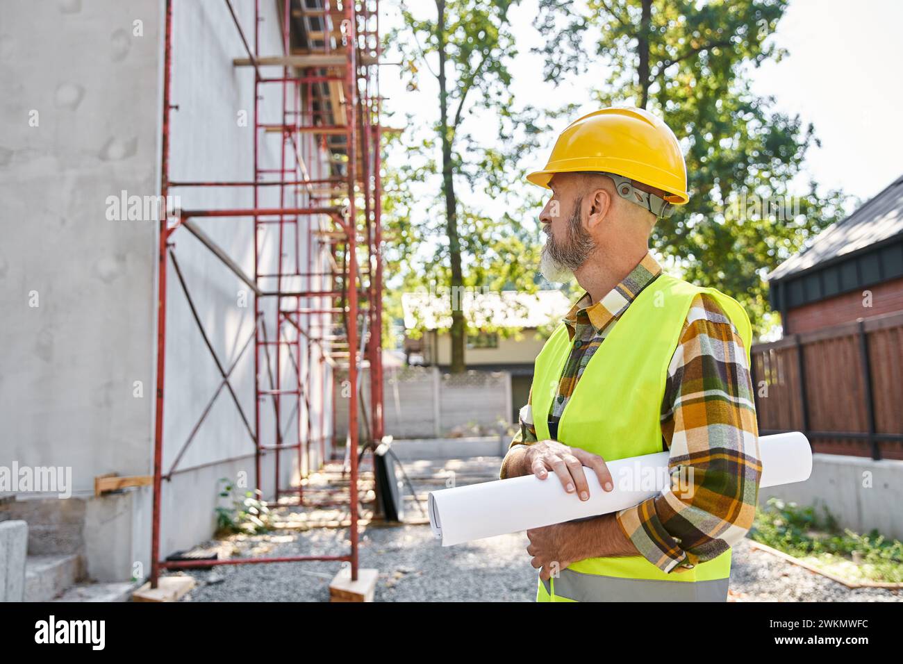 handsome construction worker in safety vest and helmet with blueprint ...