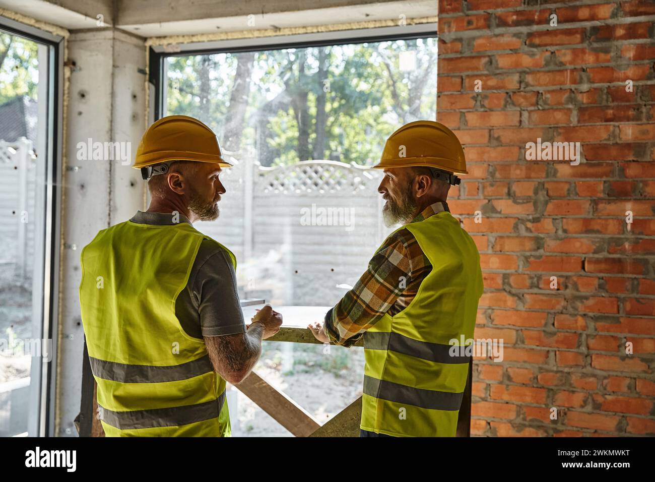 two hardworking bearded men in safety vests and helmets on construction ...