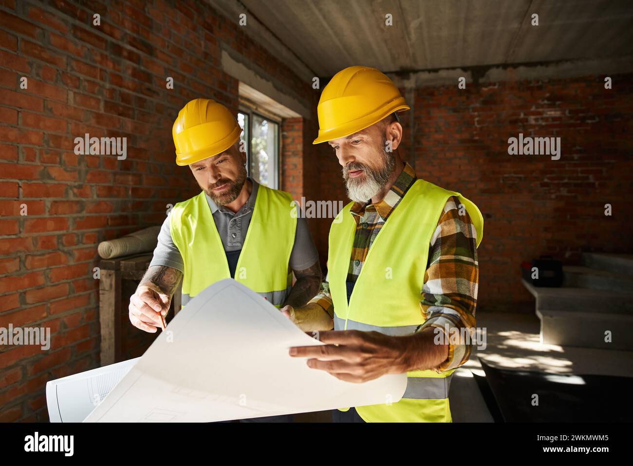 two attractive builders in safety helmets and vests working with ...