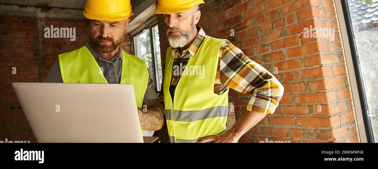 good looking construction workers in safety vests working with laptop ...