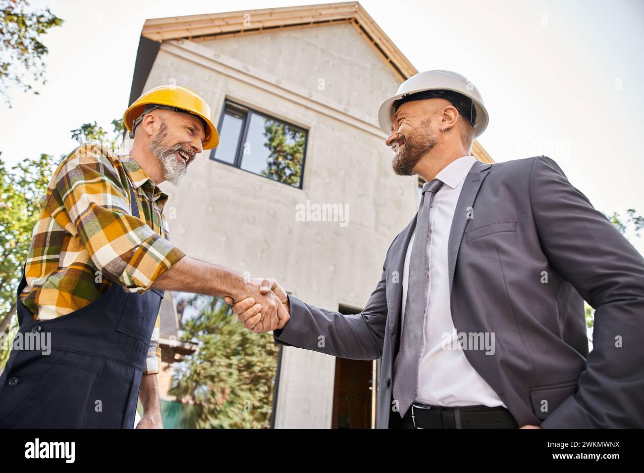cheerful handsome architect and builder in overalls and suit with ...