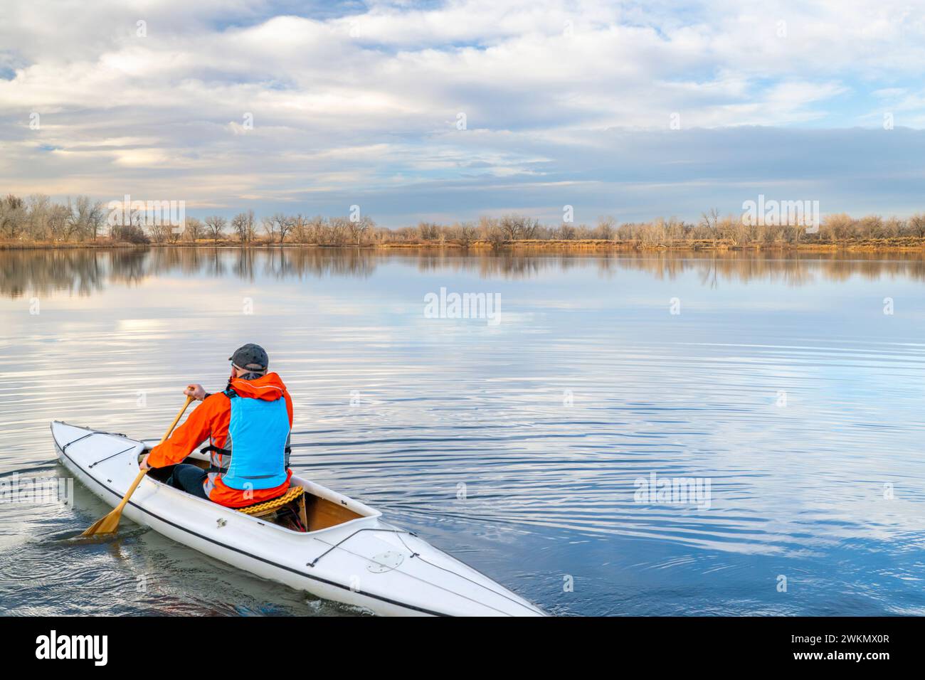 senior male paddler is paddling a decked expedition canoe on a calm ...