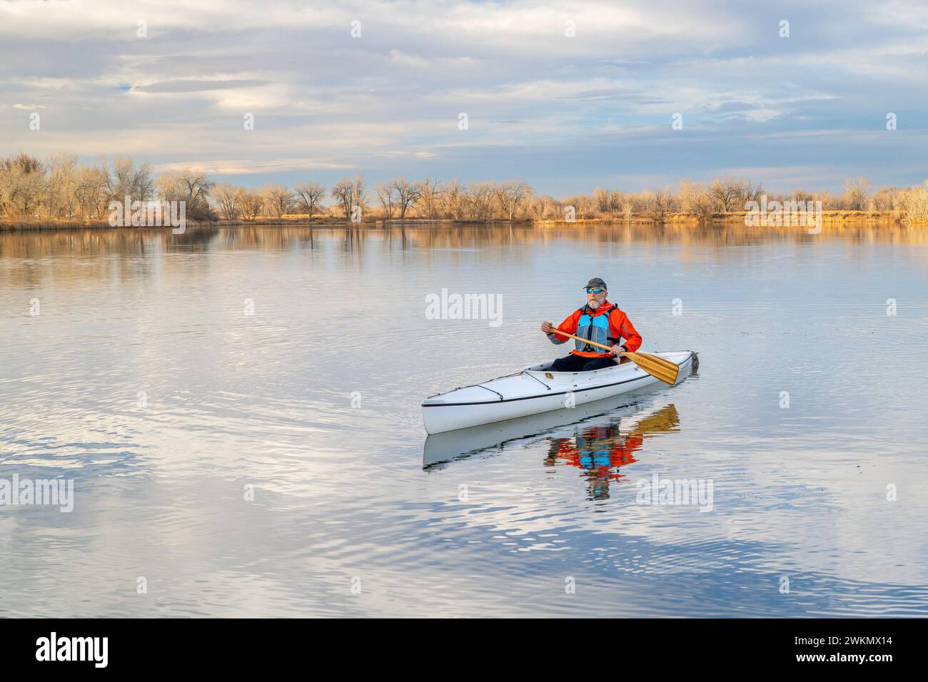 senior male paddler is paddling a decked expedition canoe on a calm ...