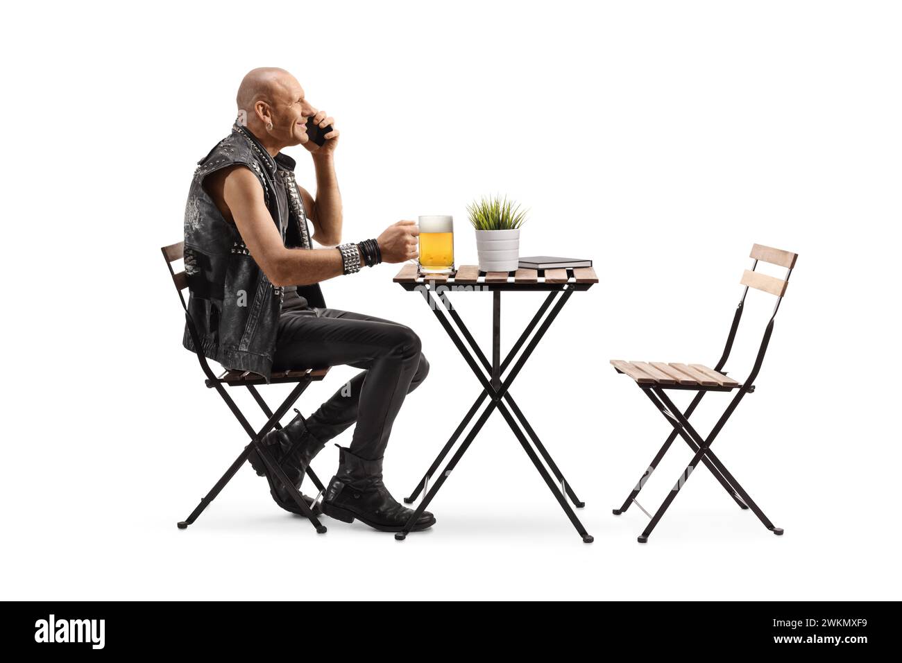 Punk with a pint of beer at a cafe table making a phone call isolated ...