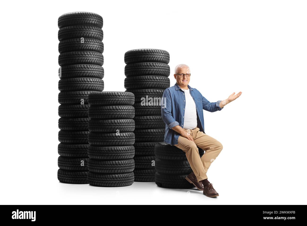 Mature man sitting on a pile of car tires and showing with hand ...