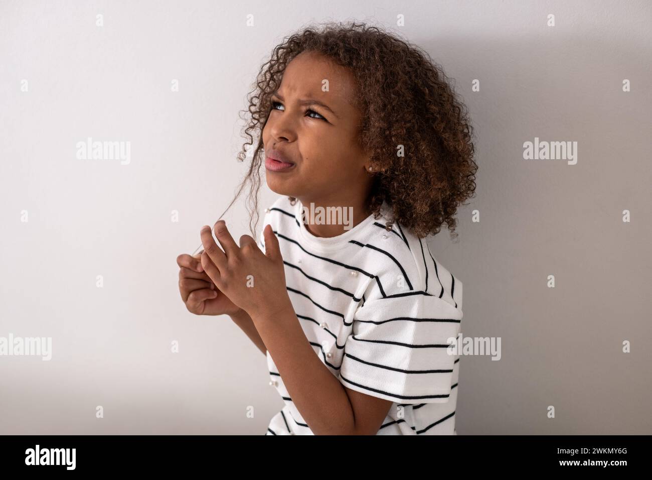 A contemplative young mixed race girl with curly hair is looking ...