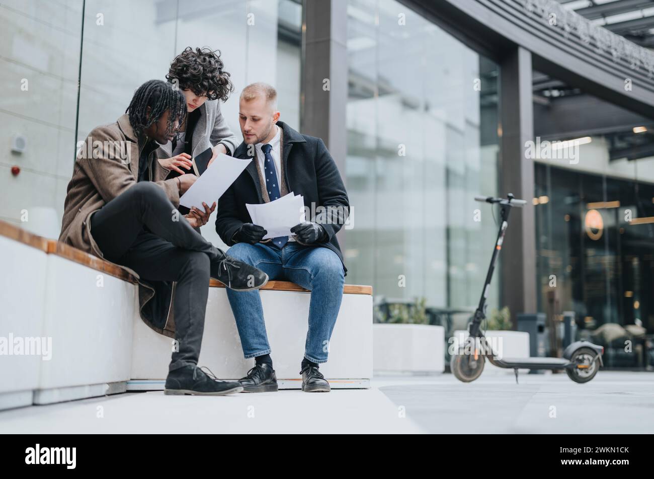 Multiracial business colleagues reviewing documents outdoors in a ...