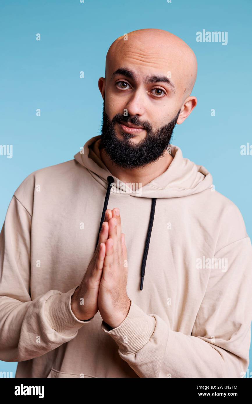 Arab man praying with hands folded in worship, expressing faith studio ...