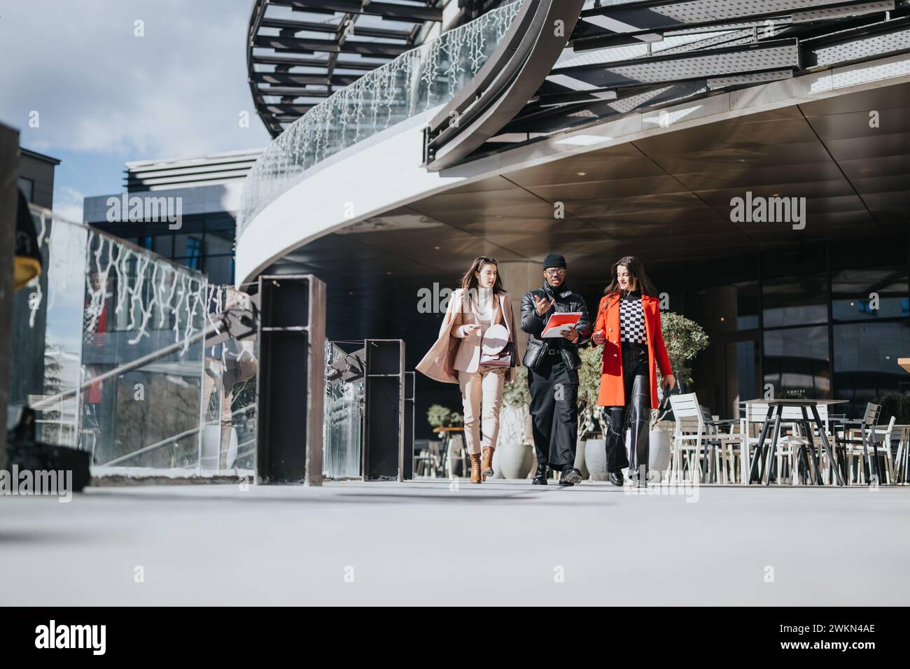 Three colleagues walking and talking outdoors in urban setting Stock ...