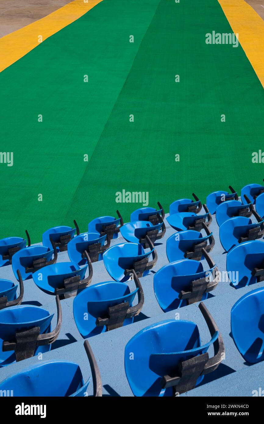 Empty blue folding spectator seats in front of synthetic green grass ...