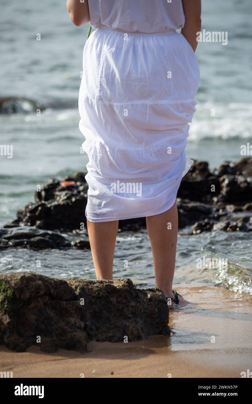 Lower part of the legs of unidentified people wet in the beach water ...
