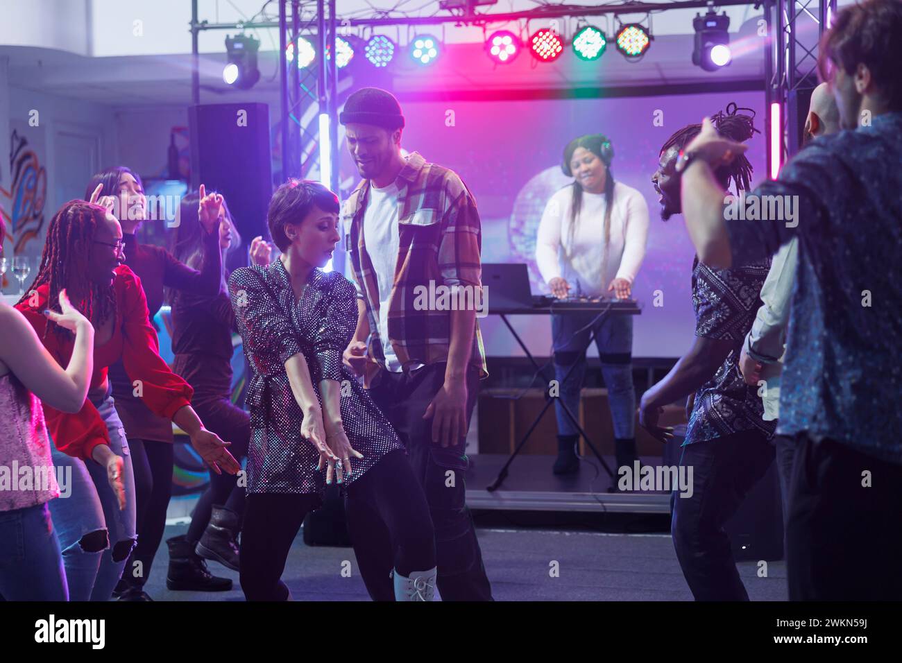 Carefree young woman dancing with friends while celebrating at disco ...