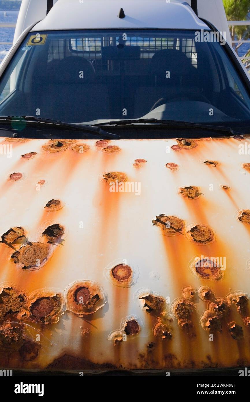 White compact size car with circular rust spots on front hood ...