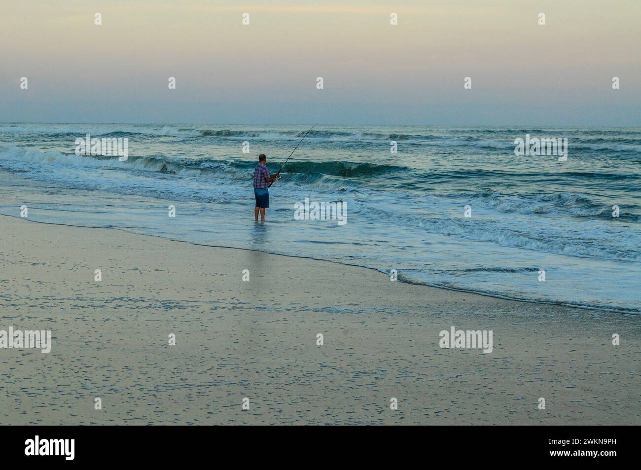 Lone fisherman at the Outer Banks at sunset at Emerald Isle in North ...