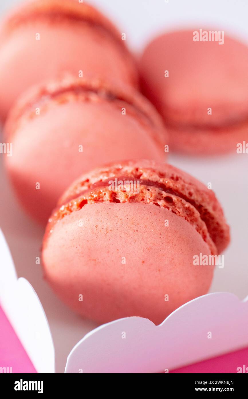 Pink macarons in a cardboard box on a pink background. French pastries ...