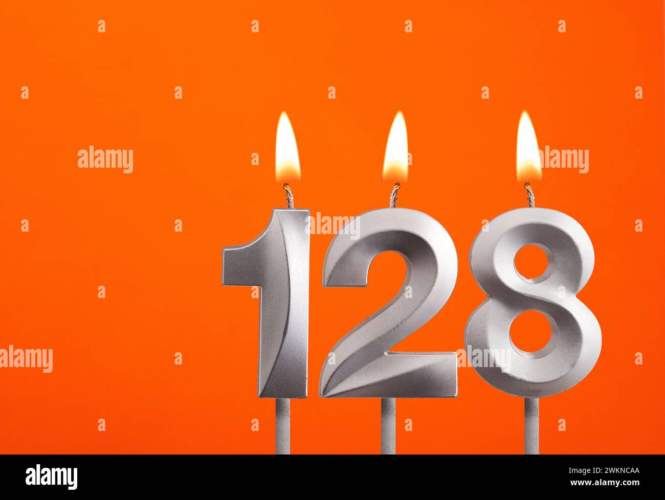 Candle number 128 - Birthday in orange background Stock Photo - Alamy