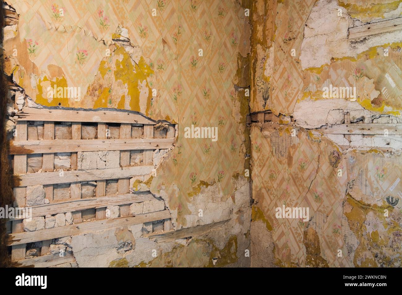 Partially demolished wallpaper, plaster and wooden lattice walls in ...